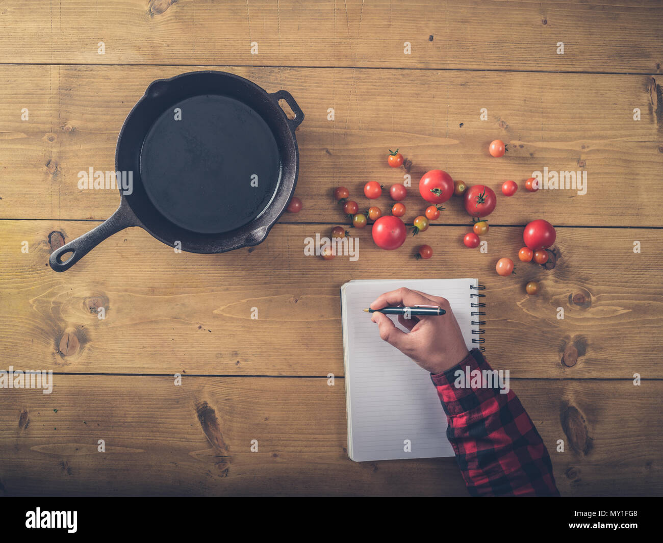 Overhead shot of a man writing down a recipe for fried tomatoes Stock ...