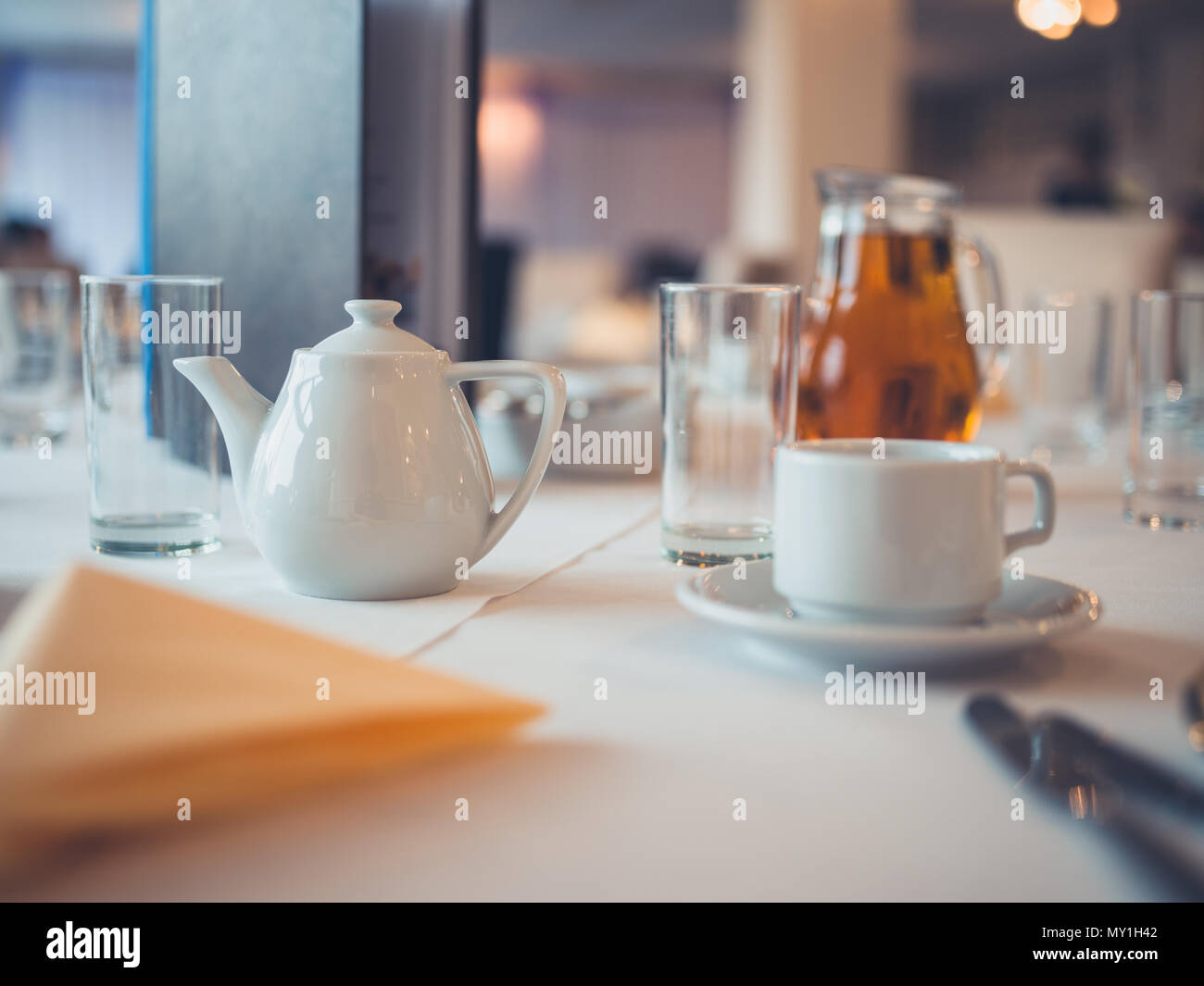 A teapot and cup on a table set for breakfast Stock Photo - Alamy