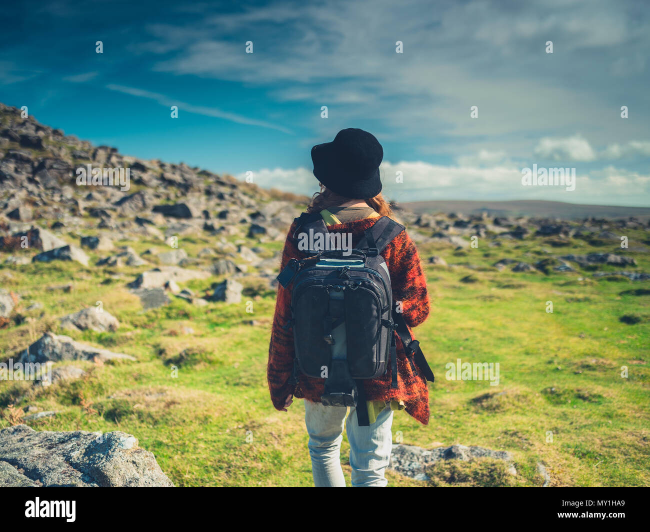 A young woman wearing a backpack is trekking through the wilderness ...