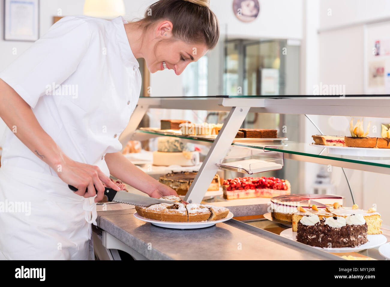 Baker sales woman putting pies and cakes on display Stock Photo - Alamy