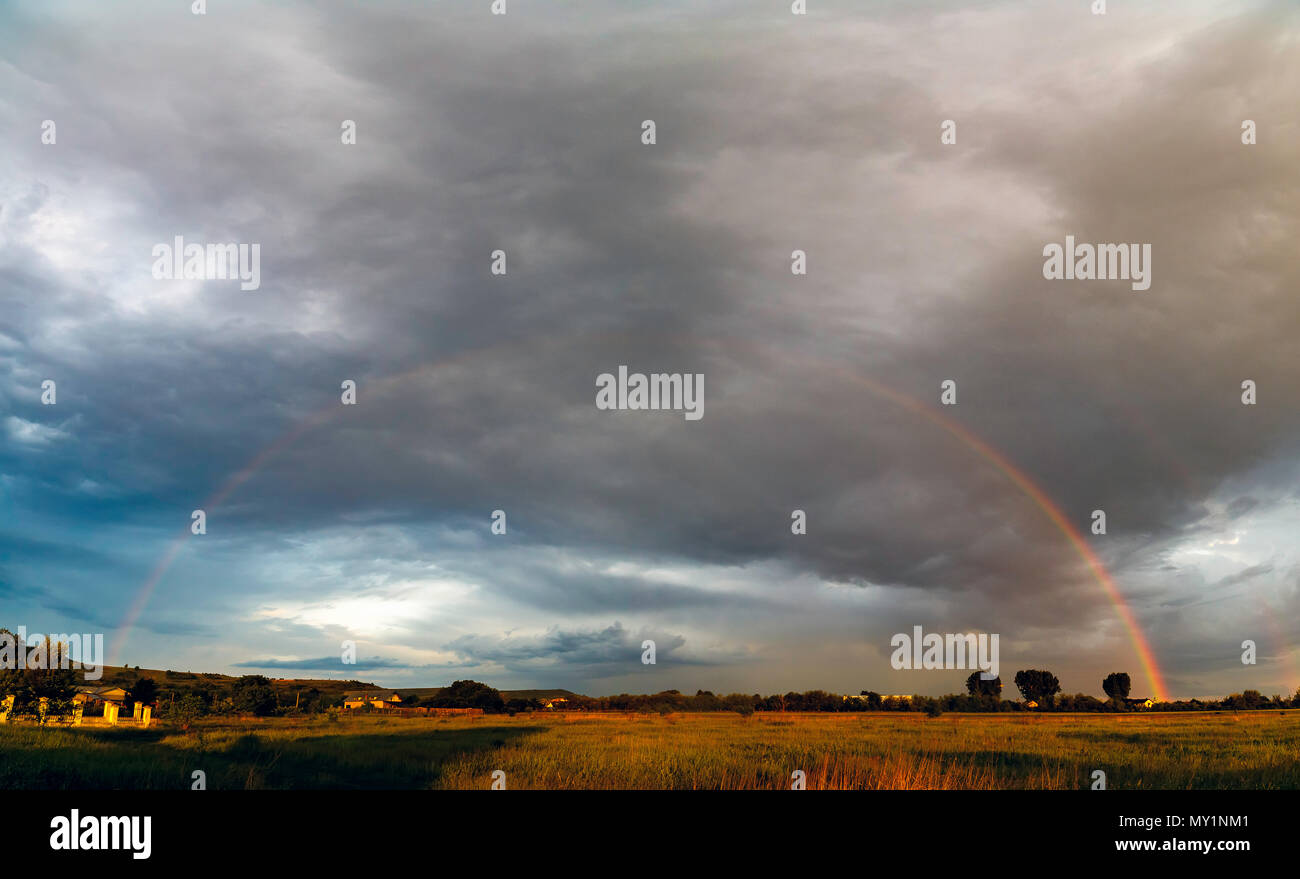 Beautiful landscape with a rainbow on a field Stock Photo - Alamy