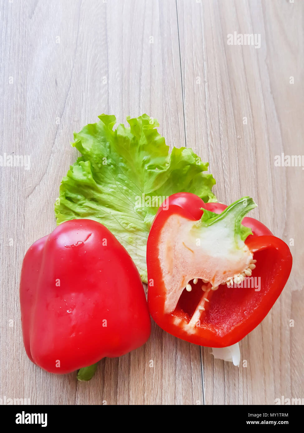 Fresh red bell pepper (capsicum) and a cut one on a table background ...