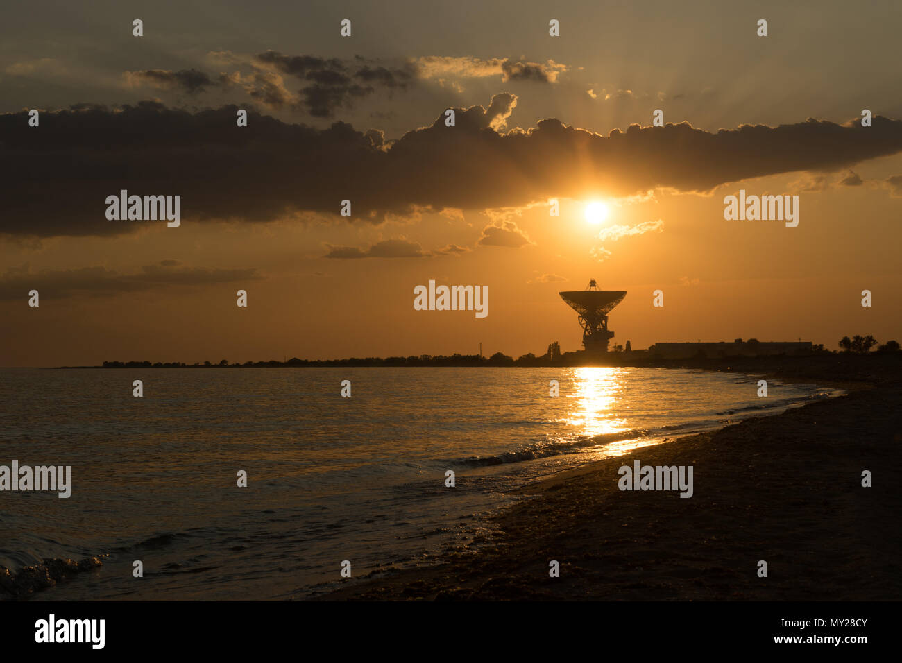 Bright sunset with sun rays on the background of a space antenna ...