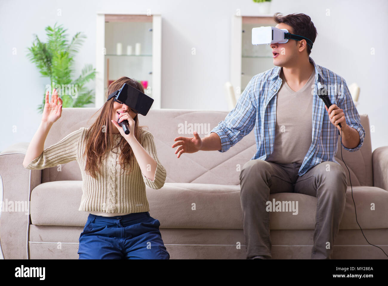 Pair singing karaoke with virtual reality glasses Stock Photo - Alamy