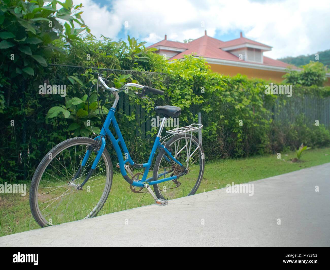 Blue bicycle left standing along a road in a suburb of Victoria in the ...