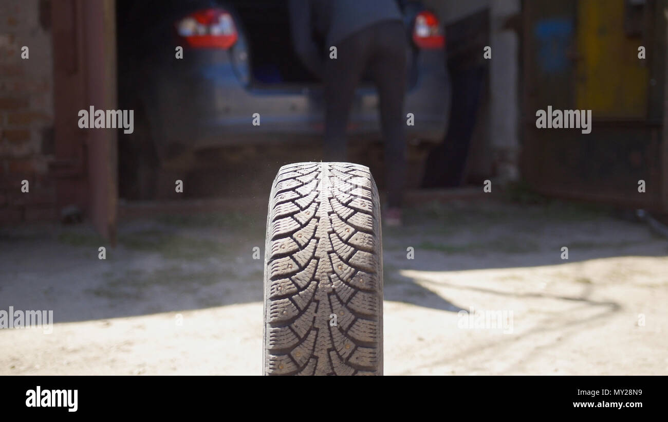 Car wheels rolling on the ground in front of car garage Stock Photo - Alamy