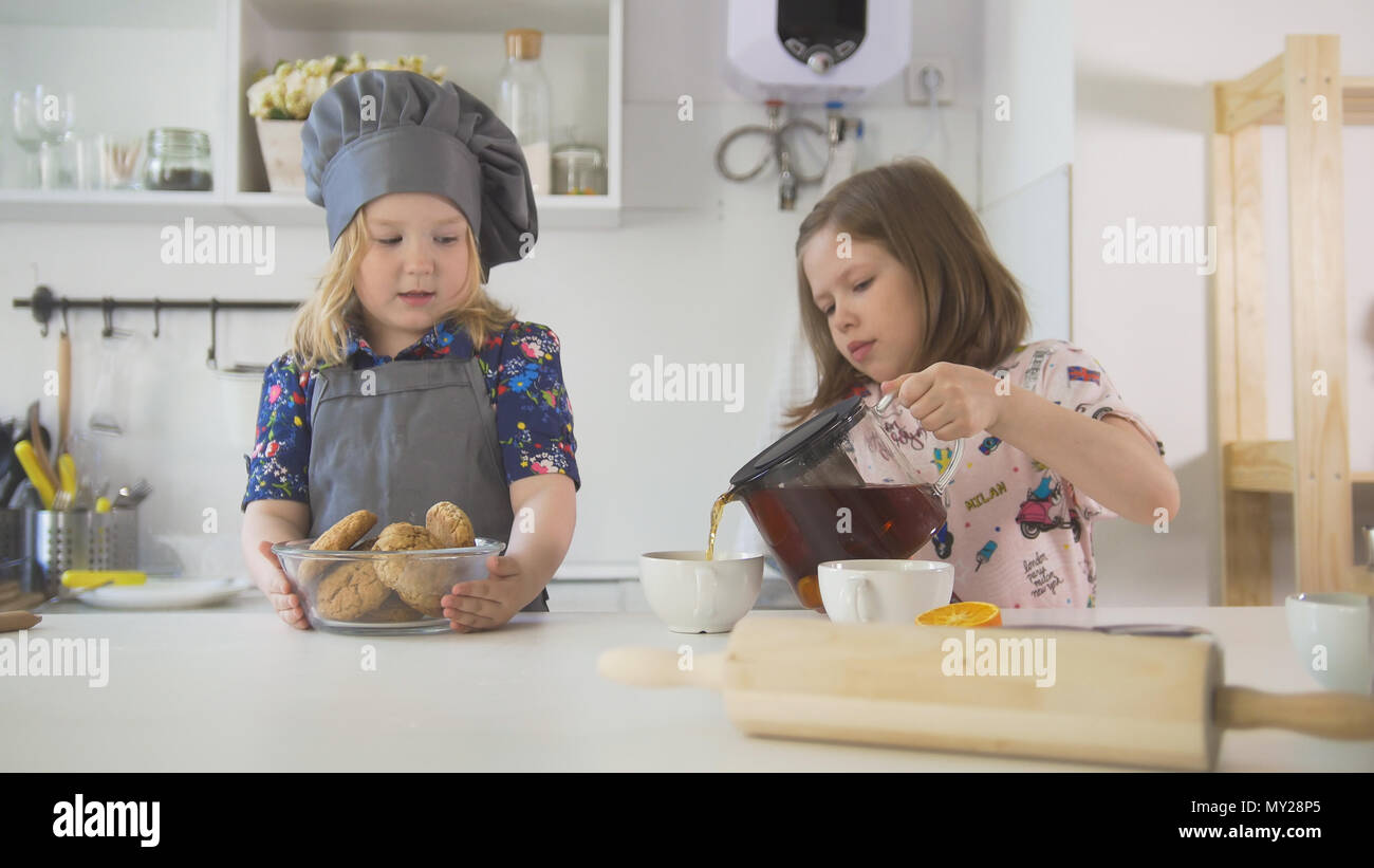 Two cute little girls decorating cookies with jam Stock Photo - Alamy