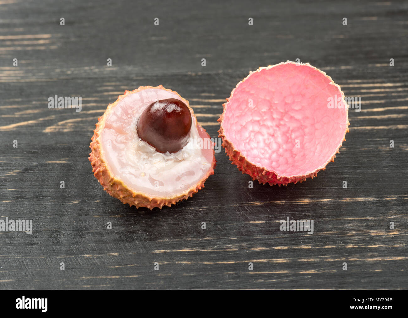 Chinese lychee fruit divided into two halves on the dark table Stock ...