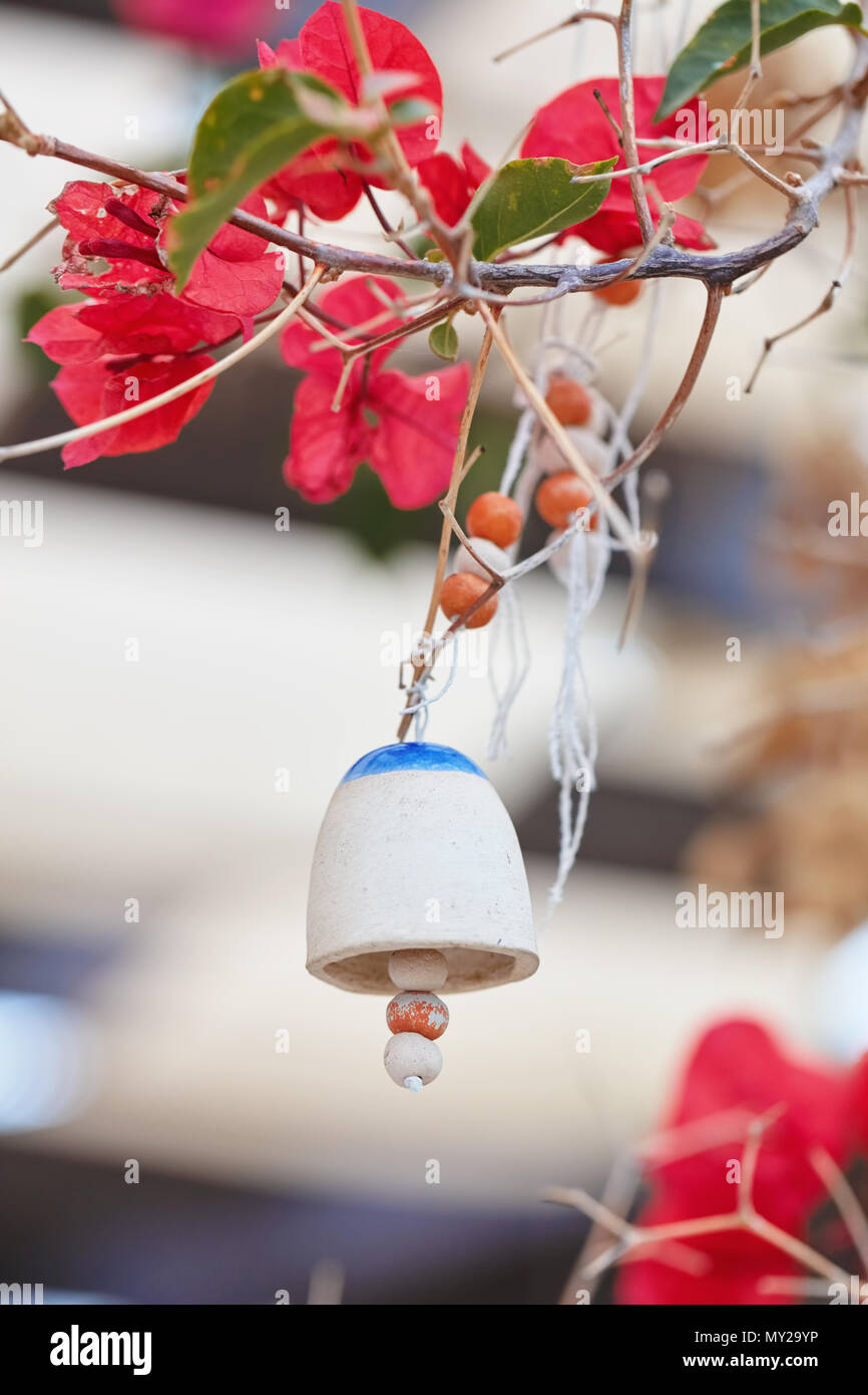 Decorative white ceramic bell ornament hanging from a cherry tree with ...