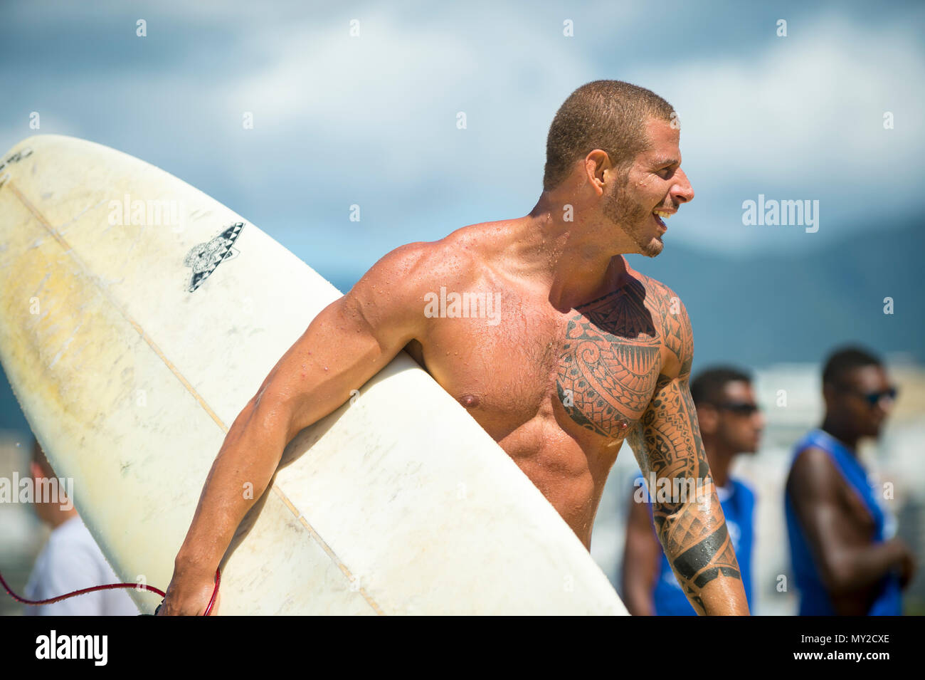 RIO DE JANEIRO - FEBRUARY 9, 2017: Surfer with tribal tattoo walks with ...