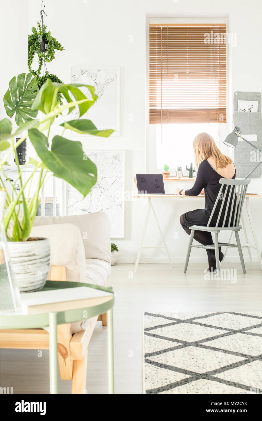Blonde girl sitting by the study corner desk with lamp and laptop in ...
