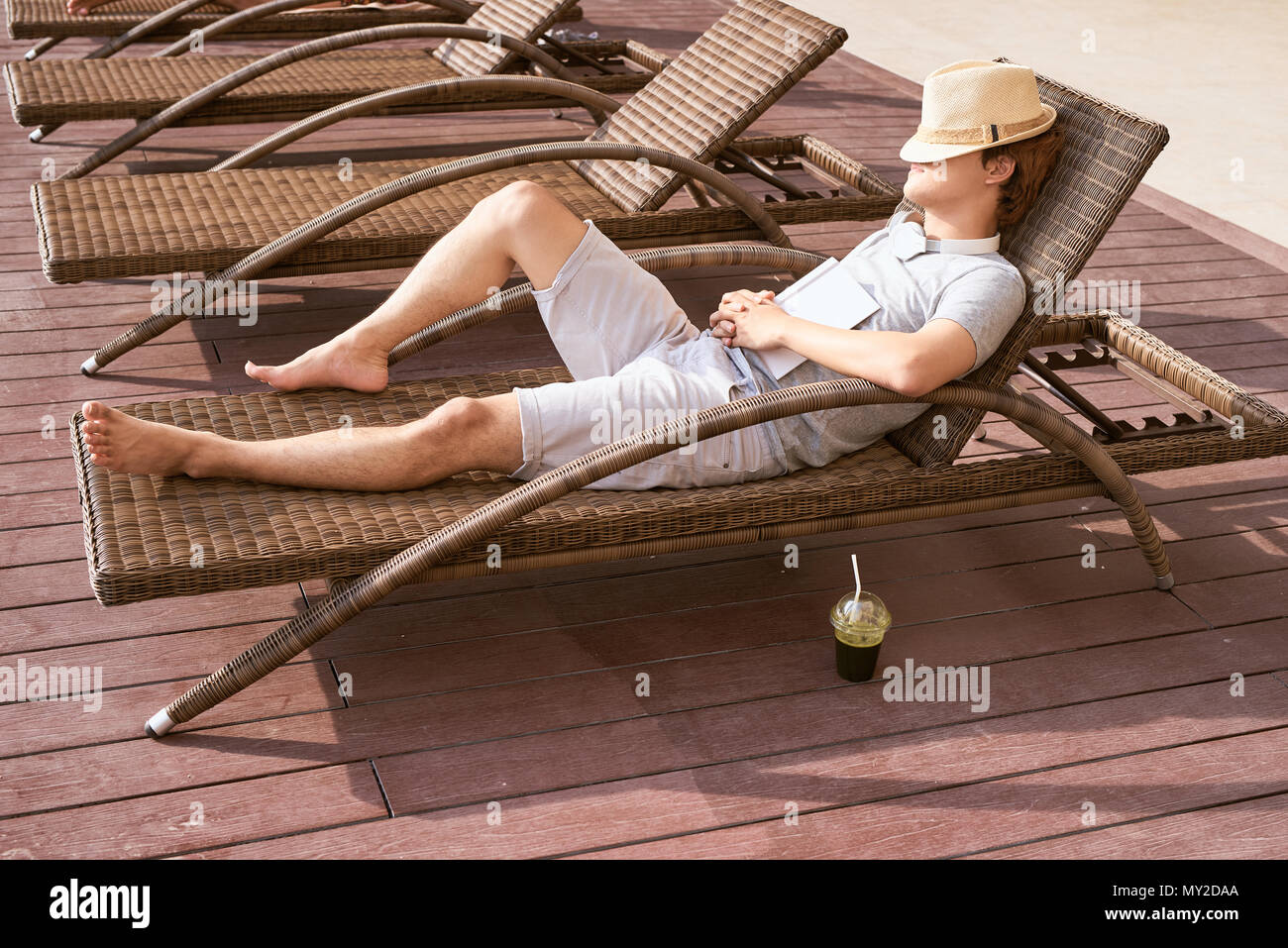 Lazy time. Asian guy sleeping on the couch swimming pool in summer ...