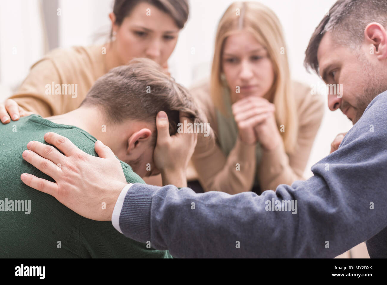 Close-up of a devastated young man holding his head in his hands and ...
