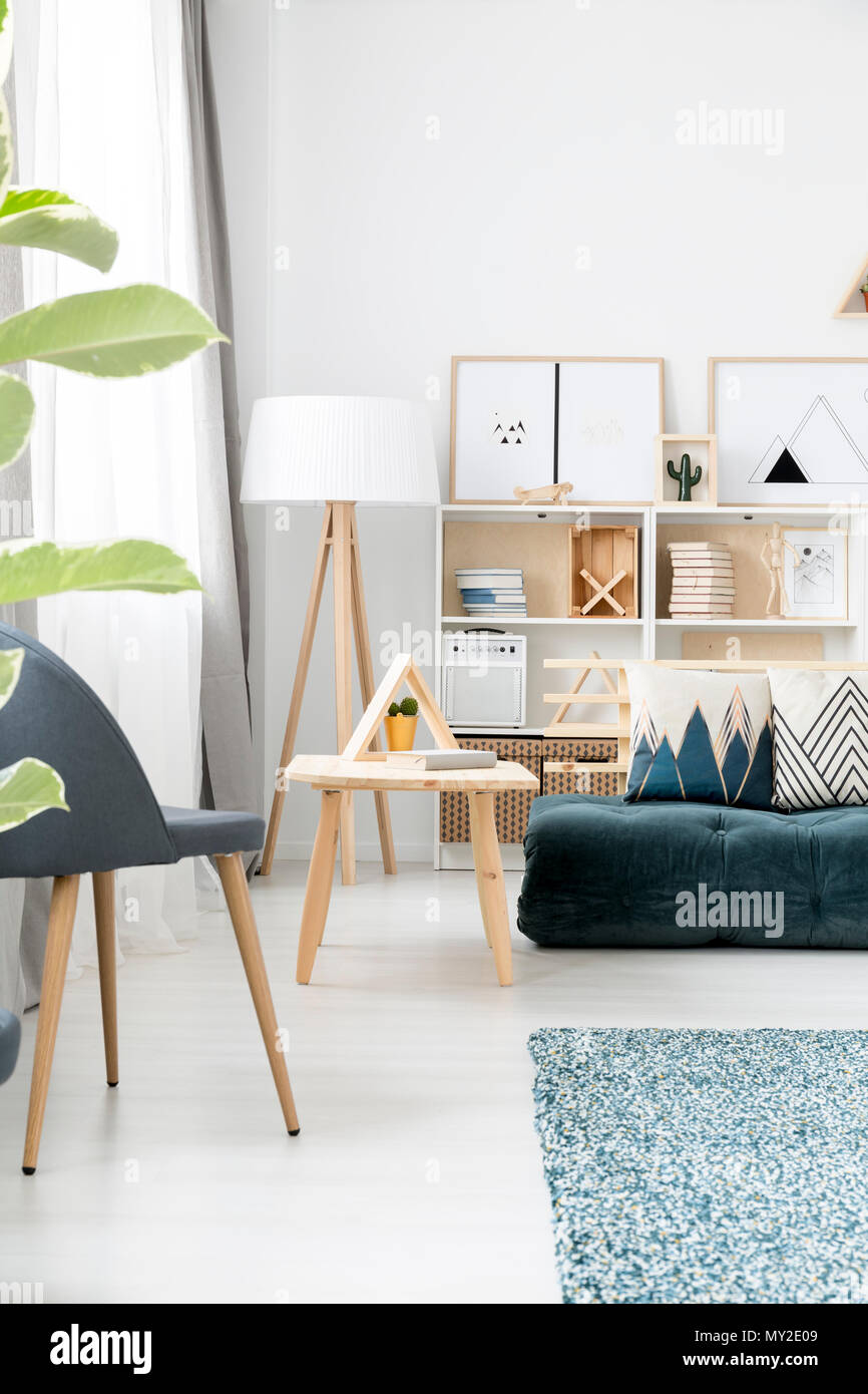 Triangle on wooden table in living room interior with chair and green ...