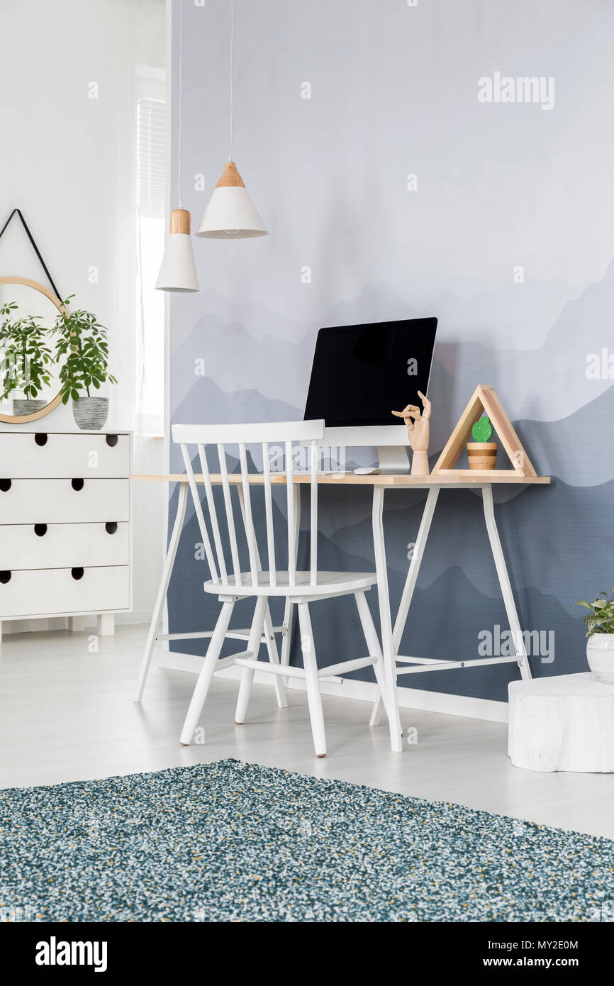White chair at wooden desk with computer monitor against mountain ...