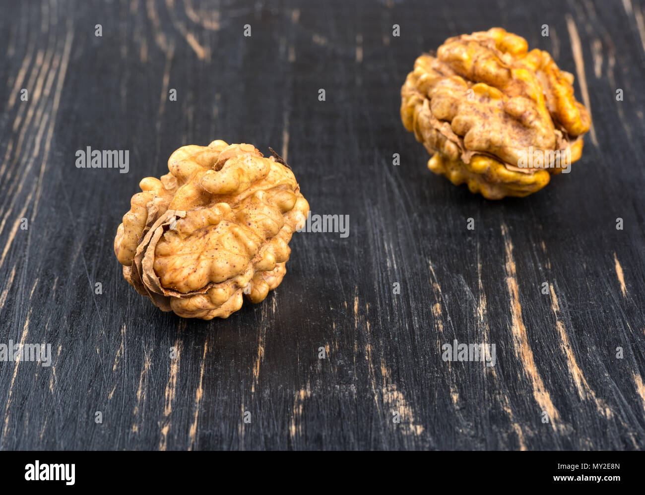 Two walnuts without shell on wooden background closeup Stock Photo - Alamy