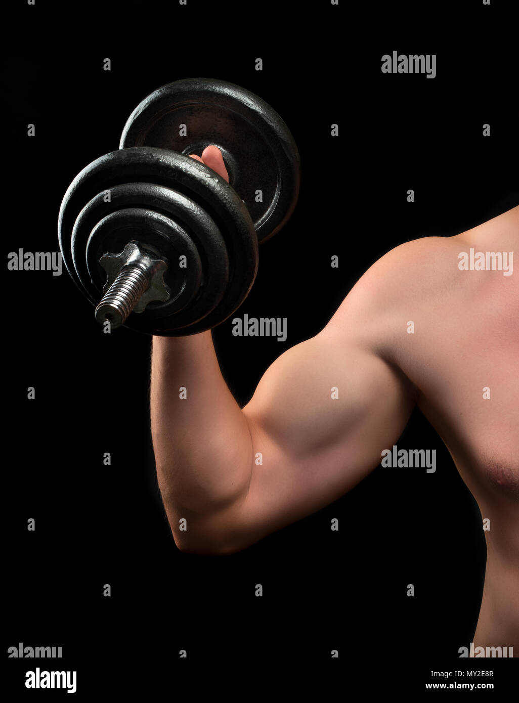 Beginner bodybuilder holds a dumbbell and showing biceps over black ...