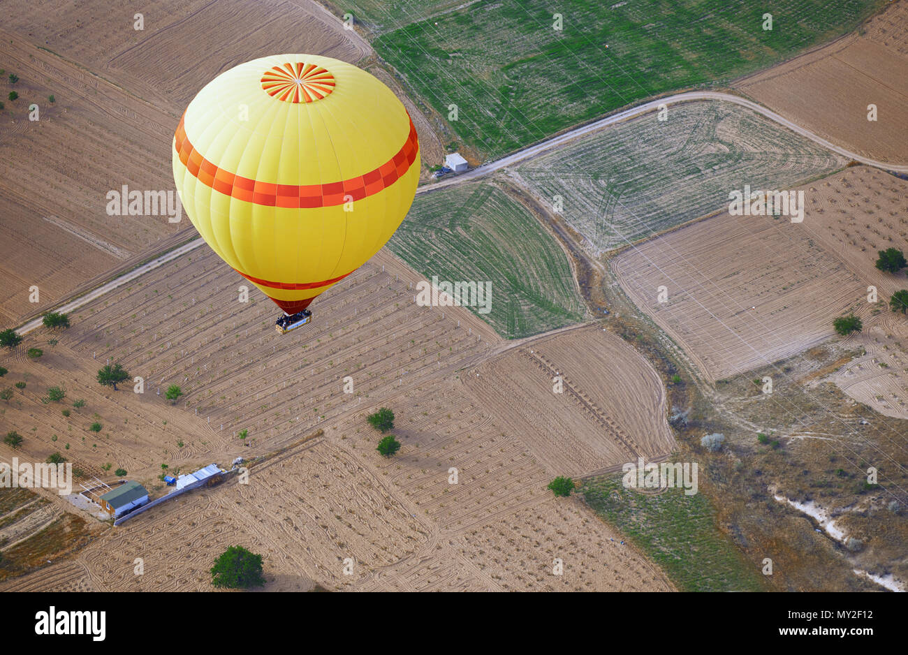 Yellow hot air balloon flying over the land Stock Photo - Alamy