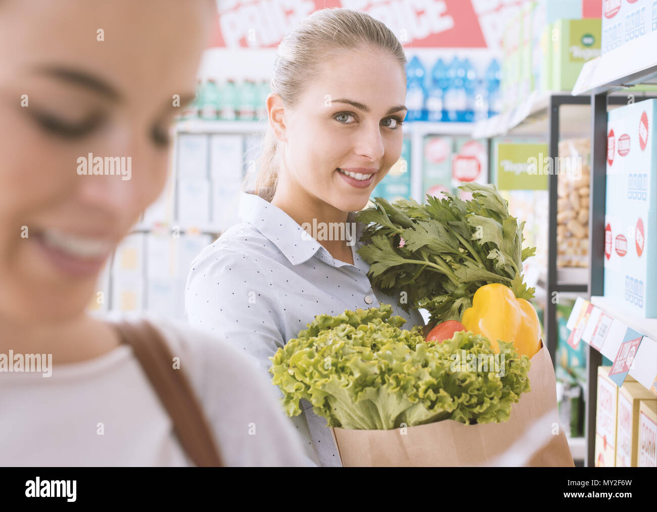 Friends doing grocery shopping together at the supermarket, one is ...