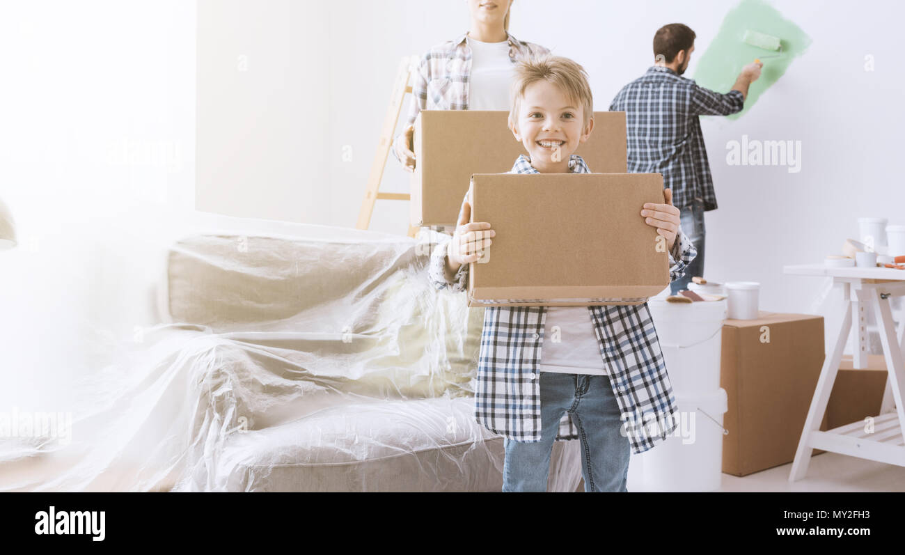 Happy family moving in a new house: they are carrying boxes and ...