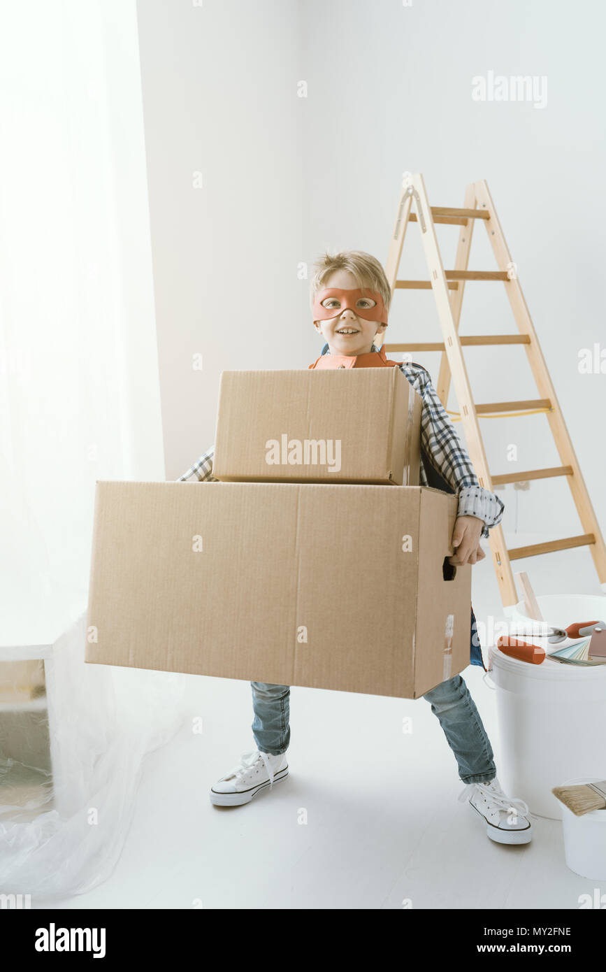 Cute superhero boy with mask and cape, he is carrying easily heavy ...