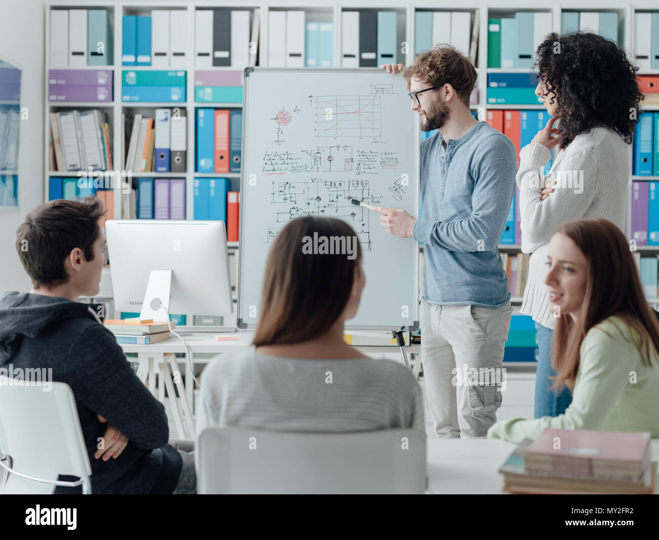 Young researcher giving a lecture to a group of university students, he ...