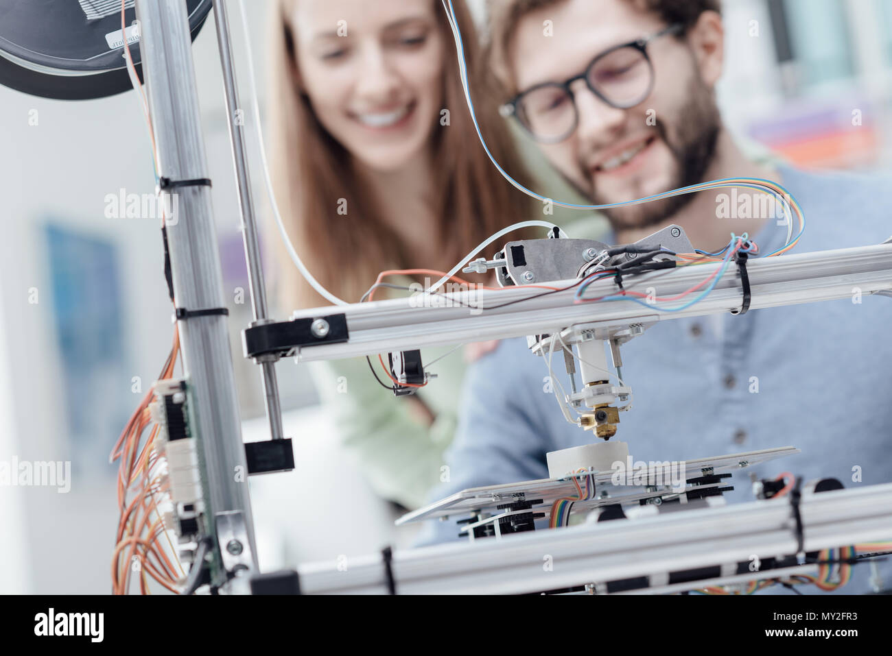 Smiling students using a 3D printer in the school laboratory, they are ...