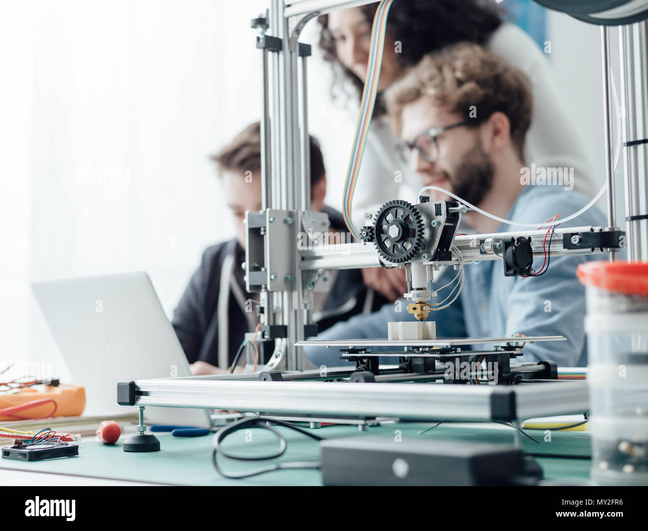 Group of engineering students using a 3D printer and a laptop in the ...
