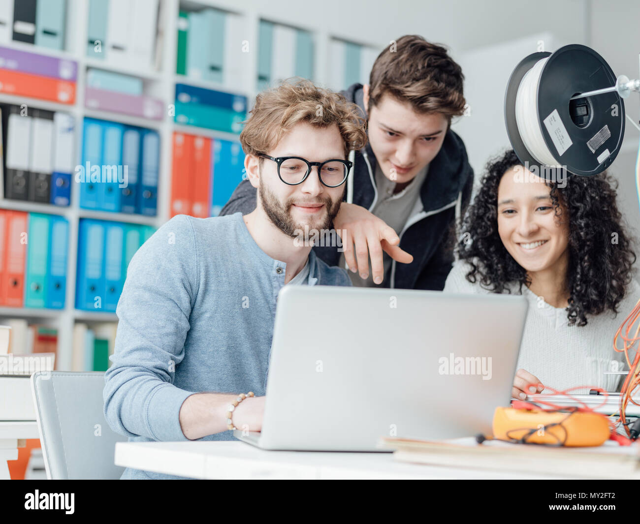 Group of engineering students using a 3D printer and a laptop in the ...