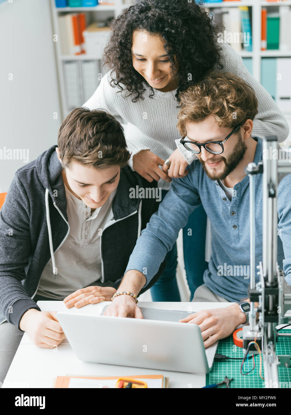 Group of engineering students using a 3D printer and a laptop in the ...