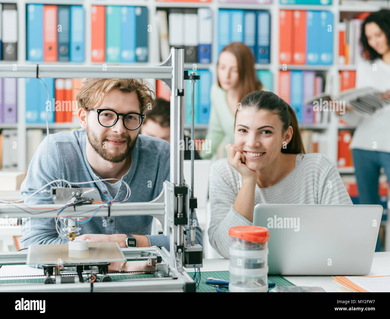 Male and female engineering students using a 3D printer in the lab ...