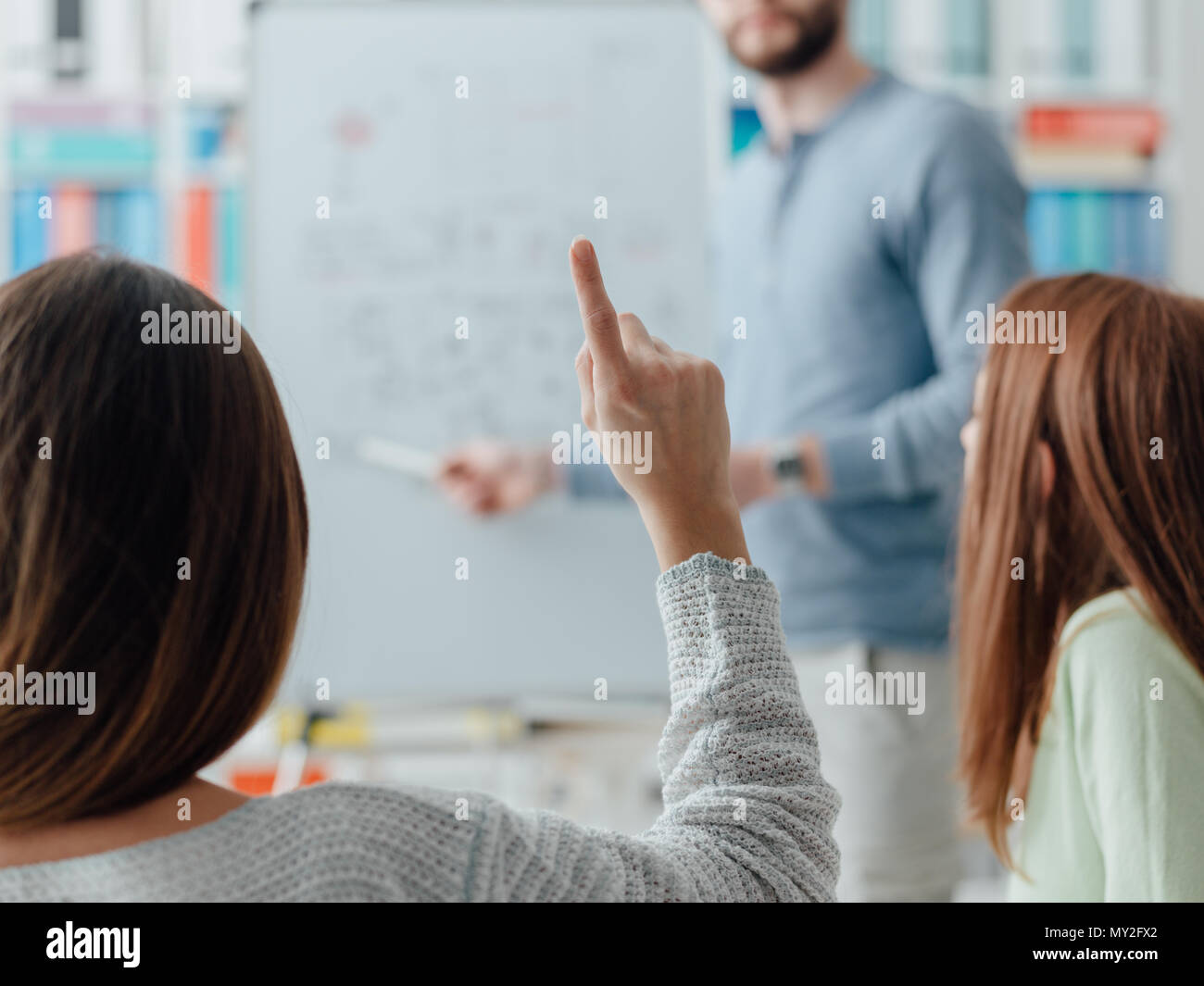 Young researcher giving a lecture to a group of students, a student is ...
