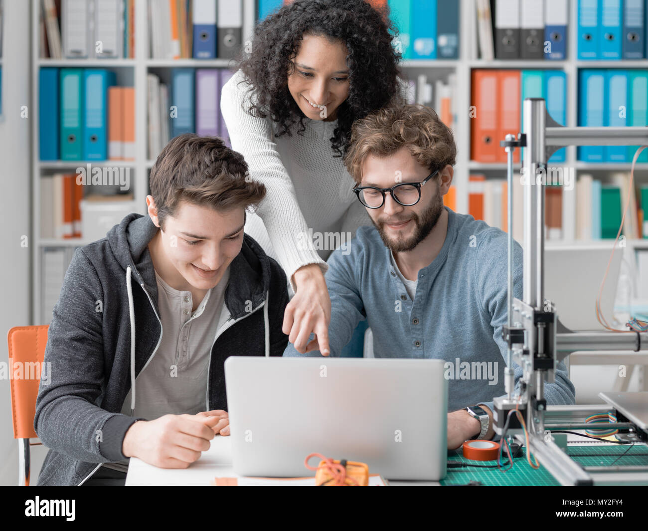 Group of engineering students using a 3D printer and a laptop in the ...