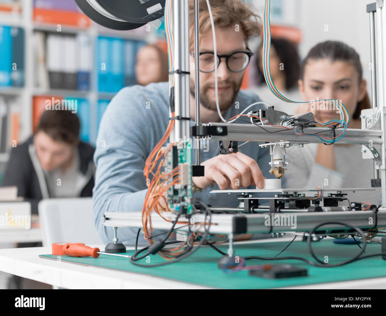 Engineering students using a 3D printer in the lab, learning and ...