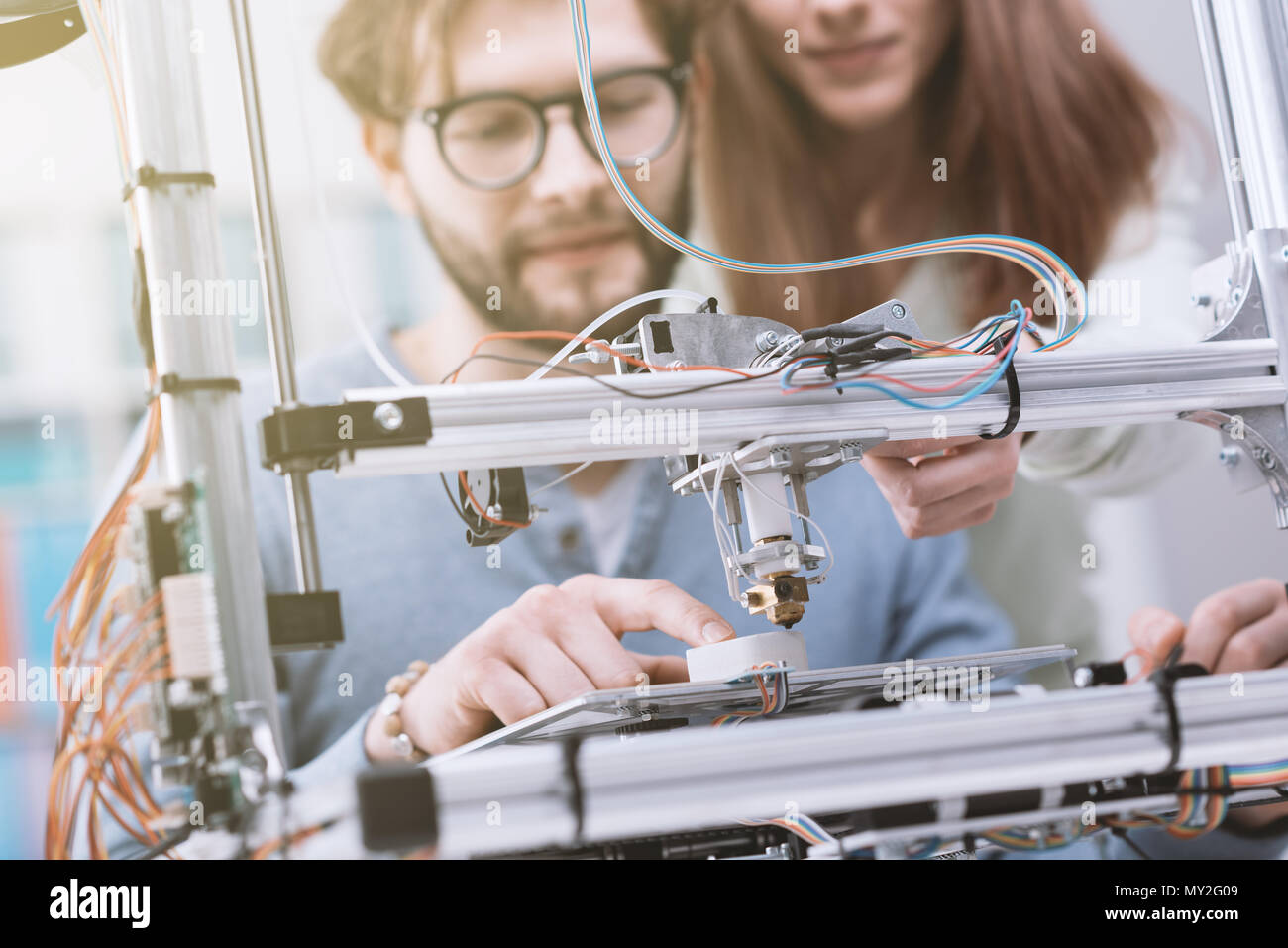 Smiling students using a 3D printer in the school laboratory, they are ...