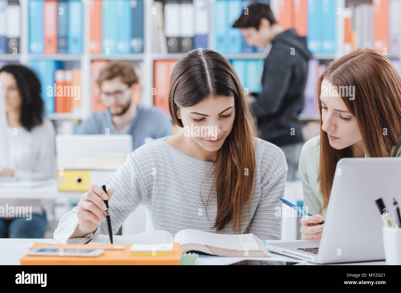 Young female students at the library, they are studying together and ...