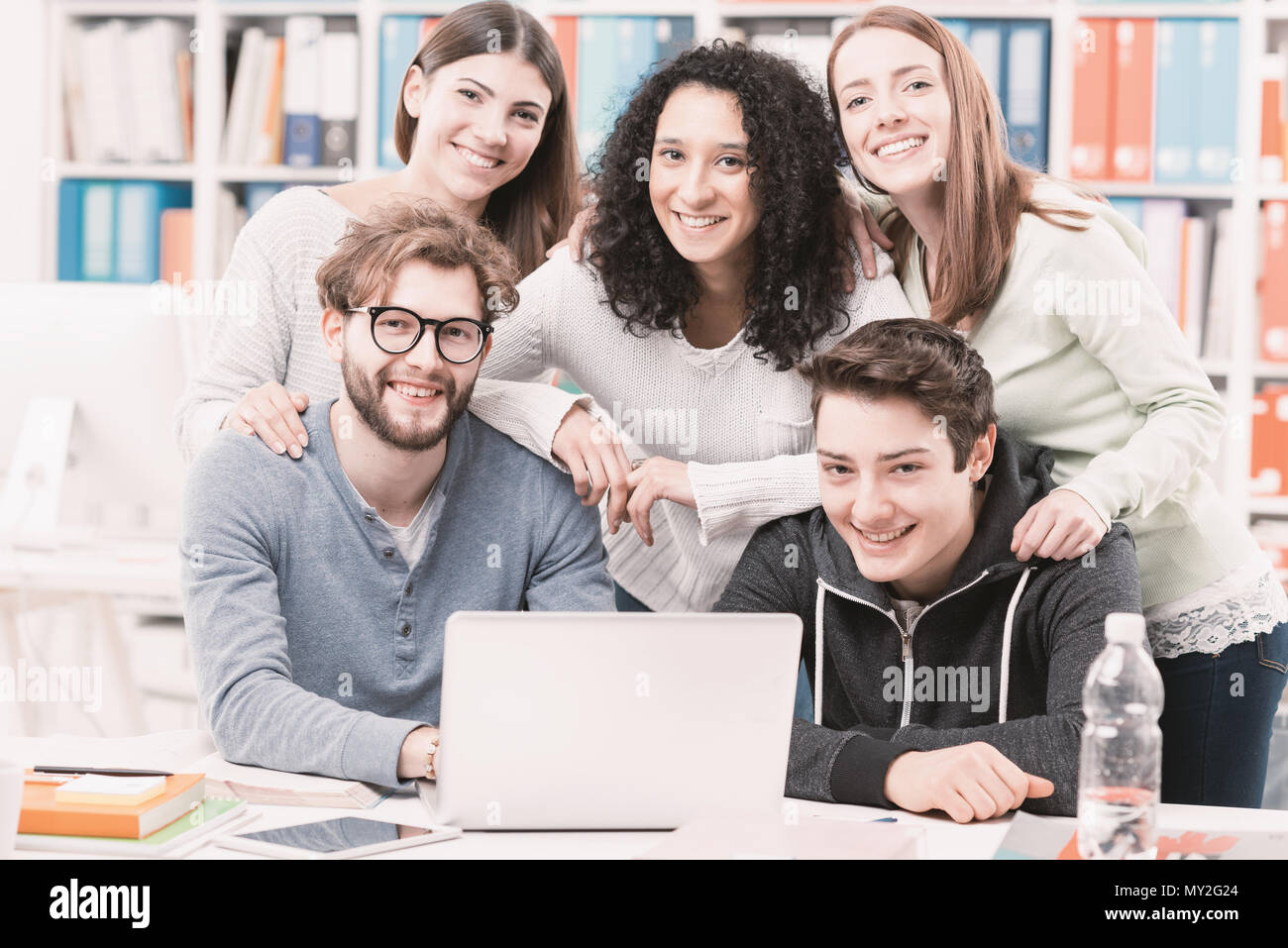 Group of happy students connecting together with a laptop and smiling ...
