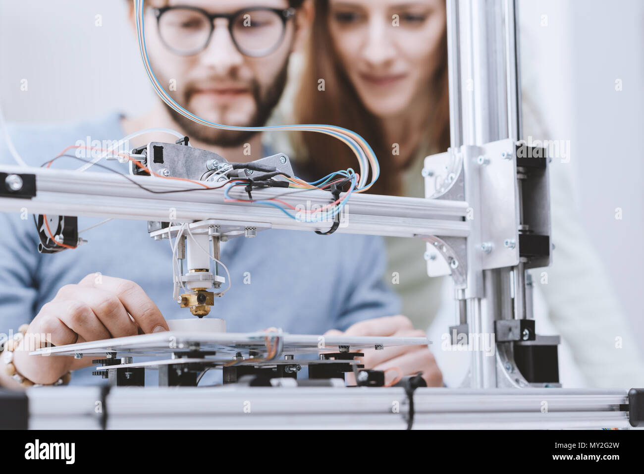 Smiling students using a 3D printer in the school laboratory, they are ...