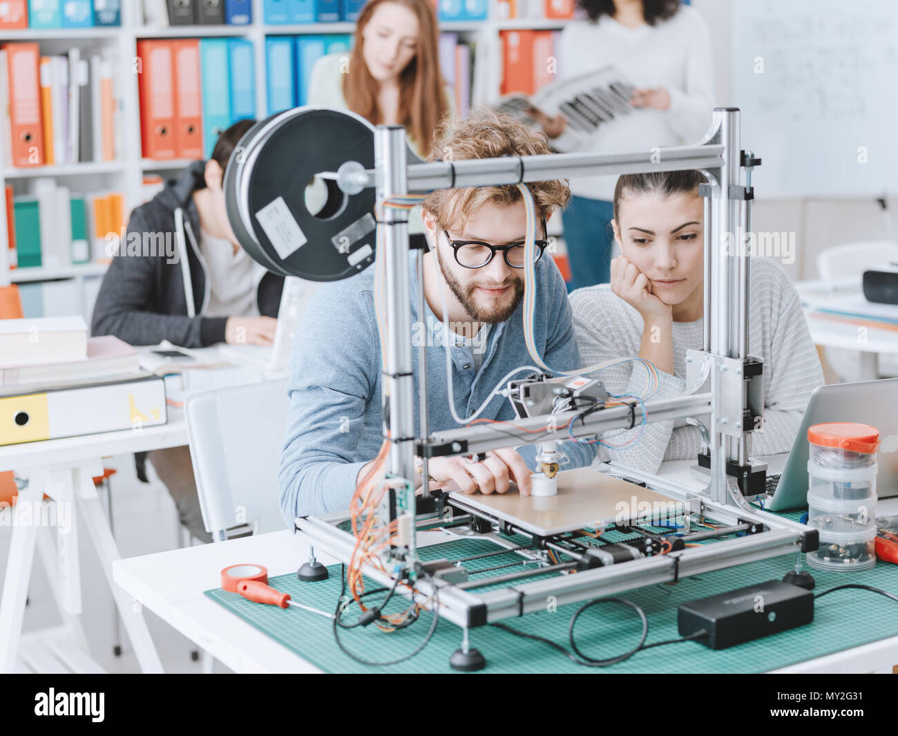 Engineering students using a 3D printer in the lab, learning and ...