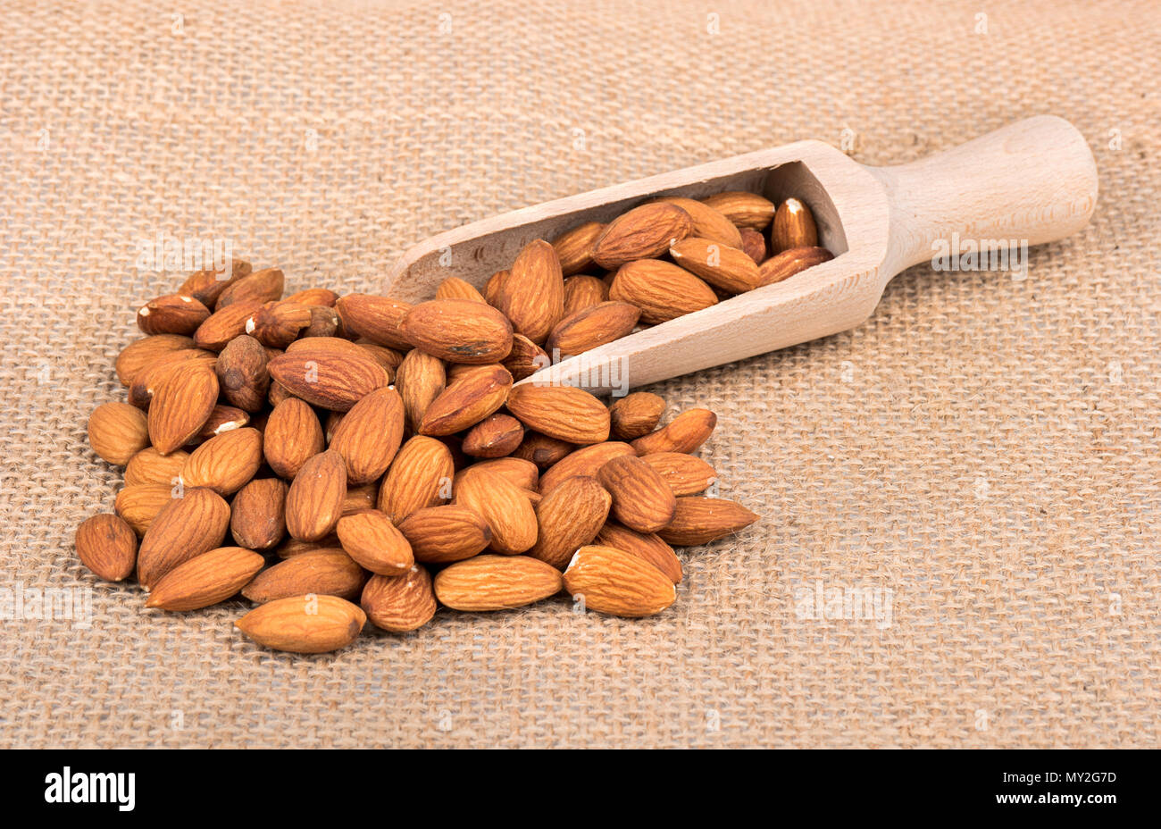 Pile of dry almonds with wooden scoop on sacking Stock Photo - Alamy