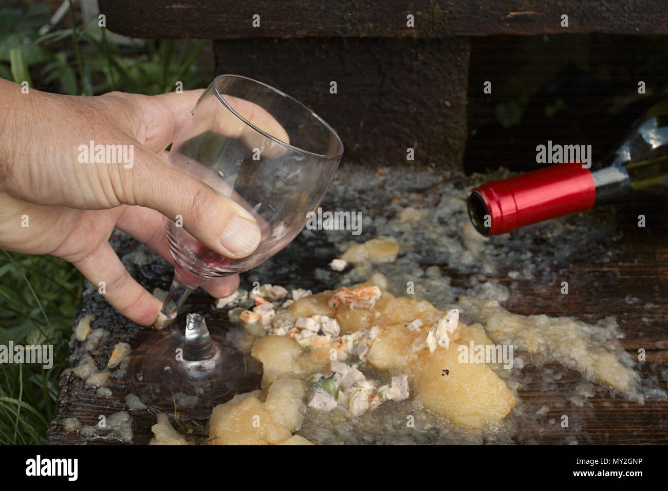 A male hand holding a broken wine glass next to disgusting vomit ...