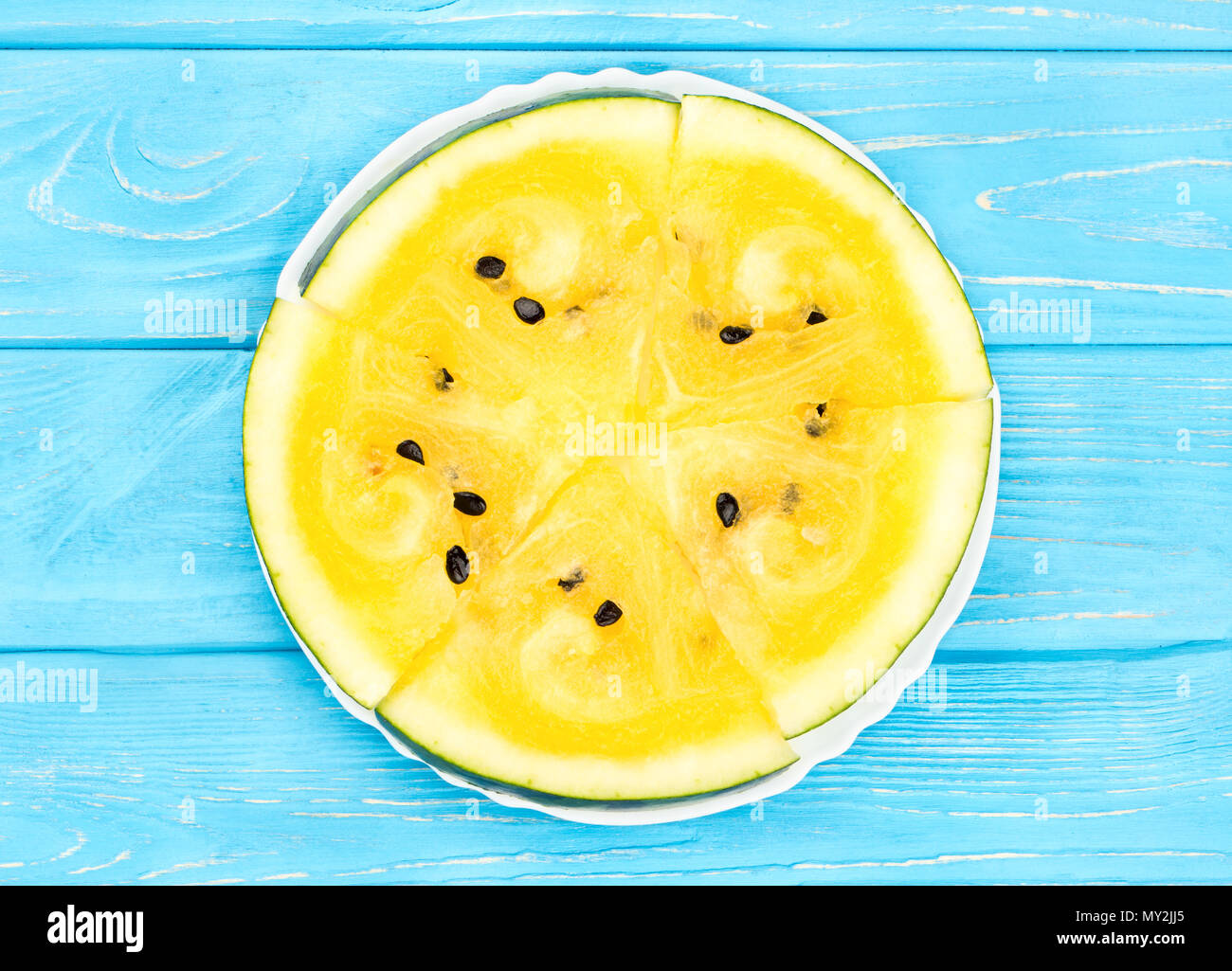 Four slices of yellow watermelon on a plate and table, top view Stock ...
