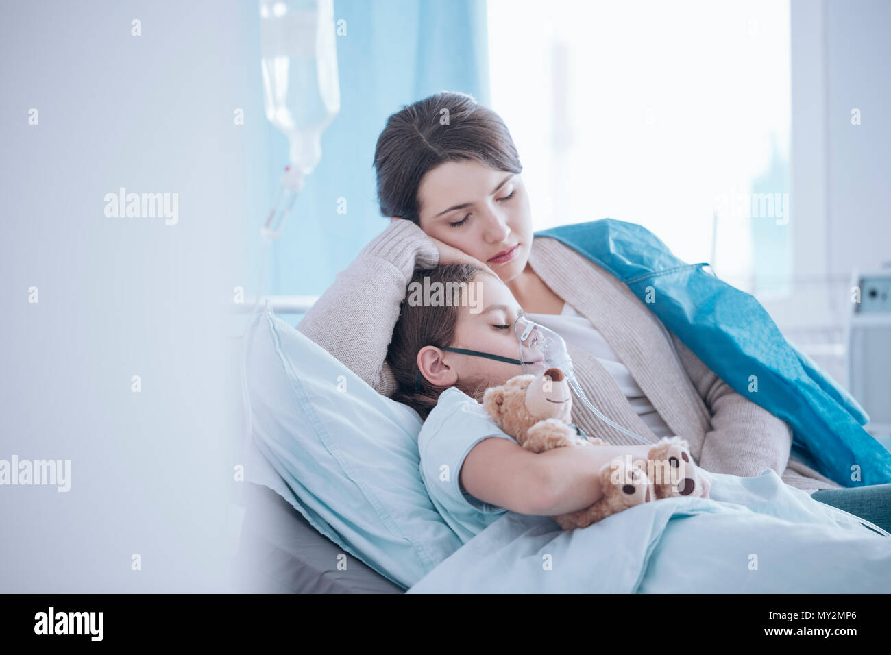 Mother taking care of sick daughter with oxygen mask and teddy bear ...