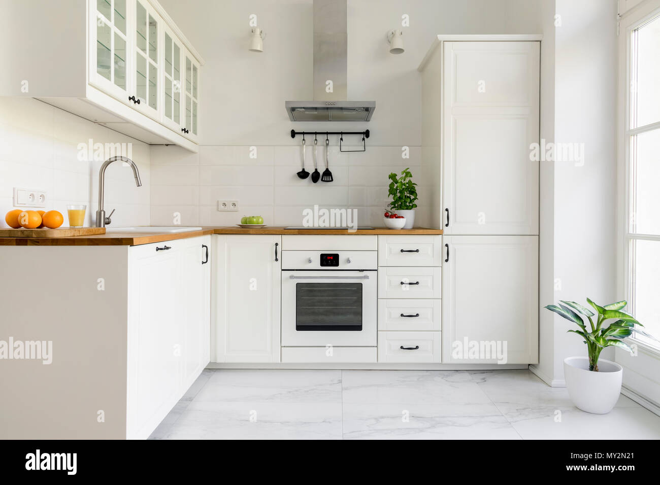 Silver cooker hood in minimal white kitchen interior with plant on ...