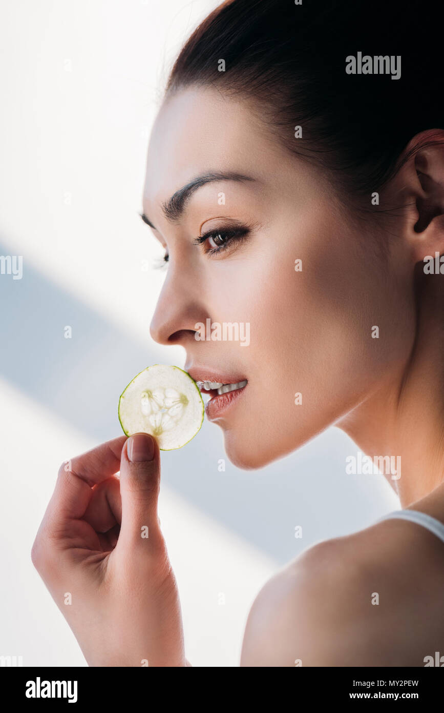 Side view shot of young woman with beautiful natural makeup eating a ...
