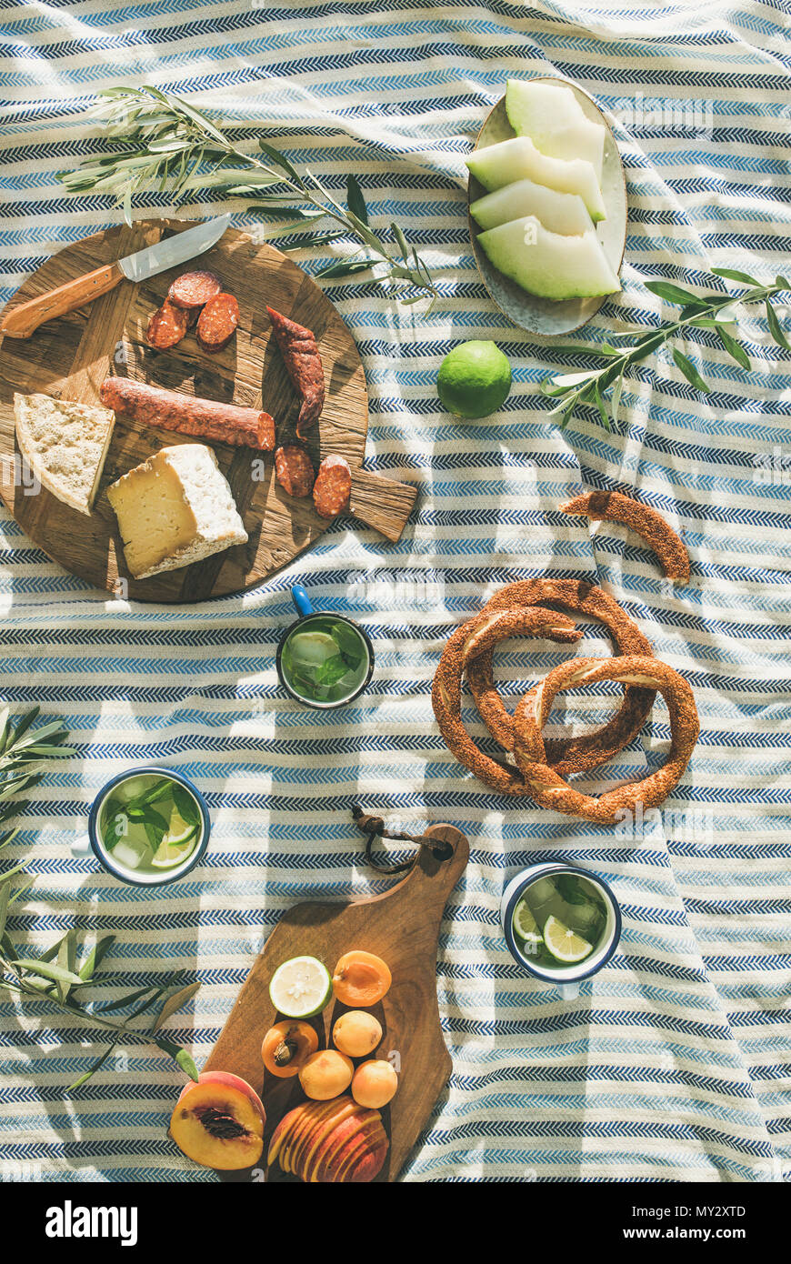 Flat-lay of summer picnic set with fruit, cheese, sausage, bagels and ...