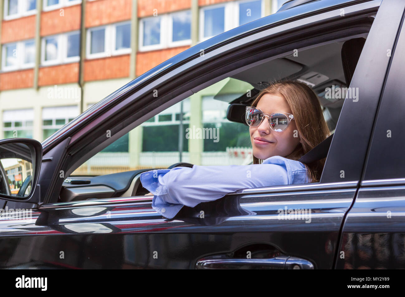 a young girl driving a car in the town Stock Photo - Alamy