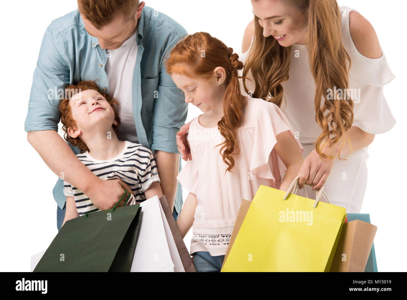 happy young family holding paper bags and smiling each other isolated ...