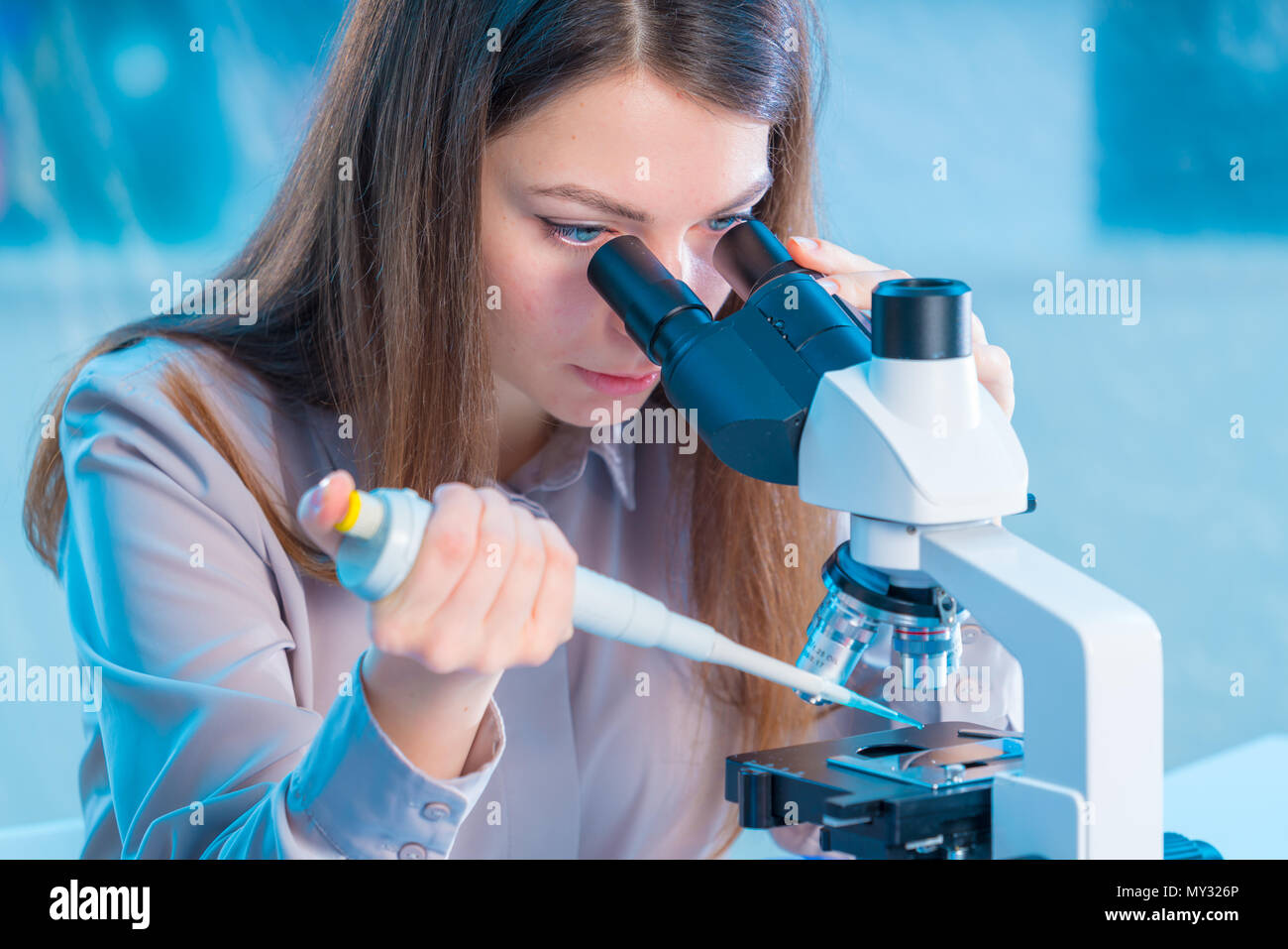 laboratory assistant with a pipette and a microscope in the laboratory ...