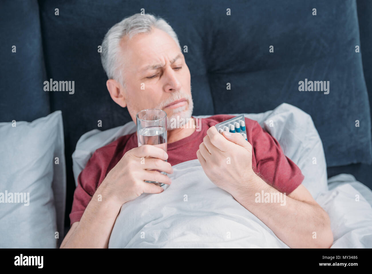 portrait of sick man with medicines and glass of water in bed Stock ...